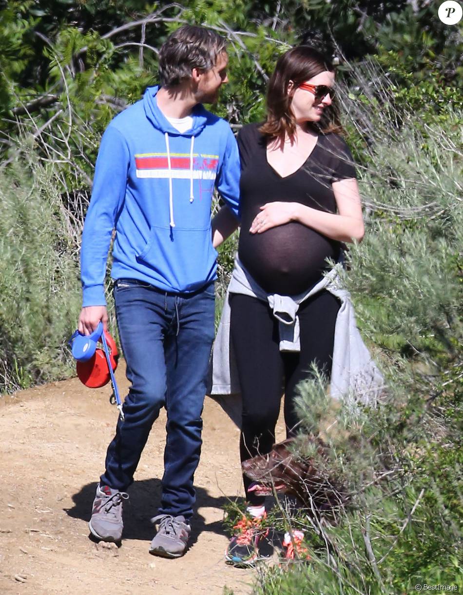 Anne Hathaway, la main sur son imposant ventre rond, se promène avec ...