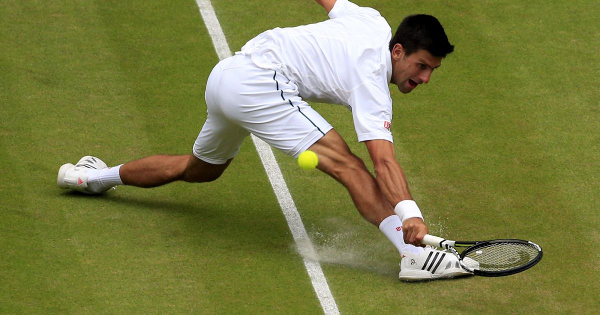 Novak Djokovic slides to make a shot against Roger Federer in the menÂ ...